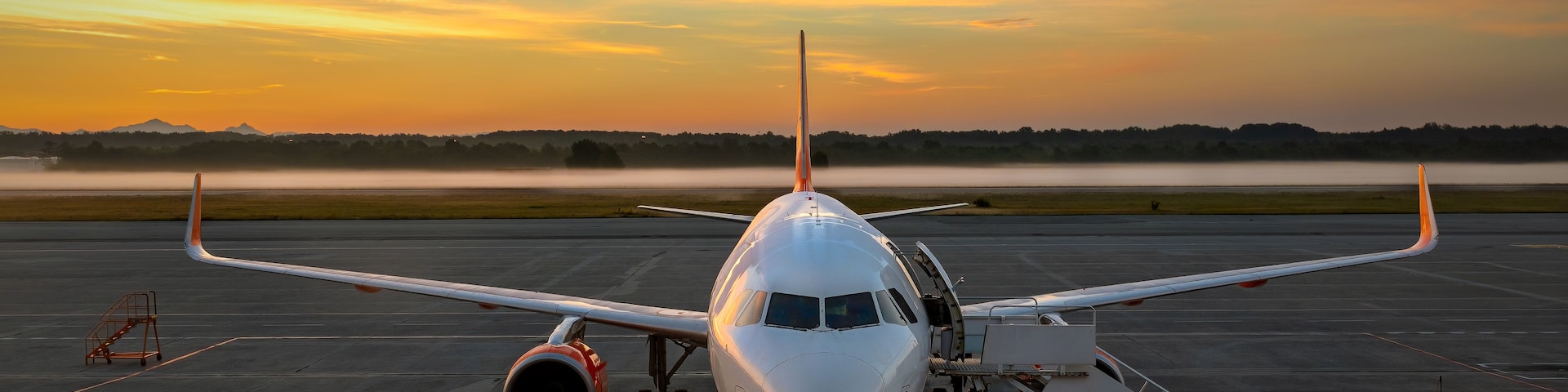 Avião na pista com um pôr do sol ao fundo.