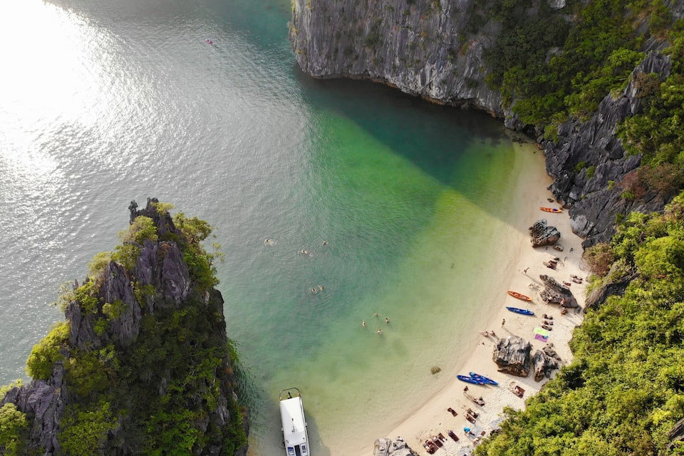 Um barco numa praia rodeada por falésias.