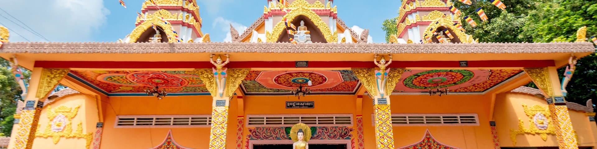 Um templo com três torres e uma grande estátua de Buda na frente.