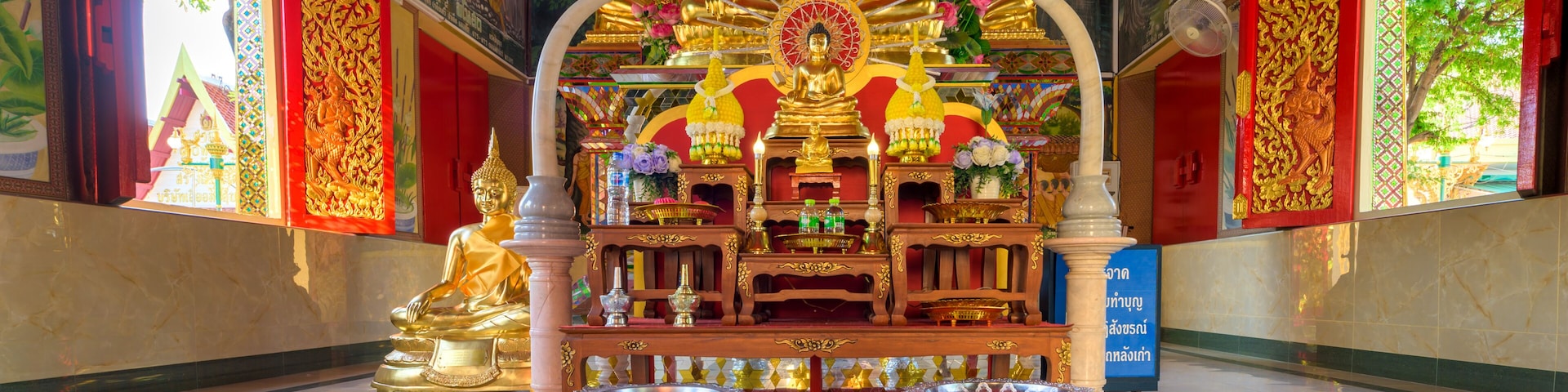 Interior de templo com estátuas douradas, altar central e pinturas detalhadas nas paredes.