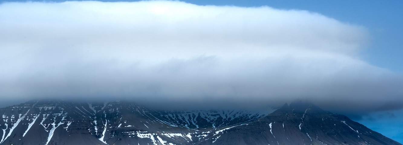 Uma estrada que leva a uma montanha com neve e céu nublado.