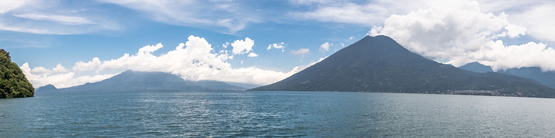 Um lago calmo com uma montanha ao fundo sob um céu parcialmente nublado.