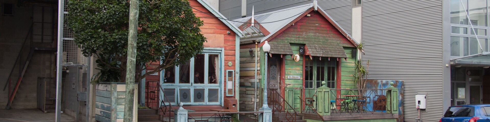 Um edifício colorido com fachada vermelha, porta verde e um pequeno alpendre.