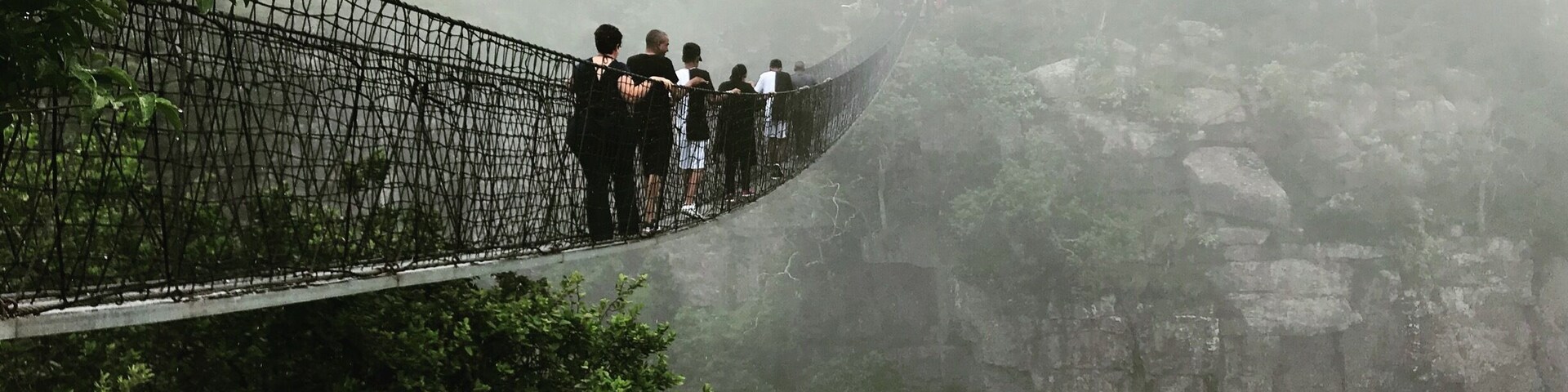 Hanging Bridge disappearing in the rain mist over an extremely high tropical gorge.