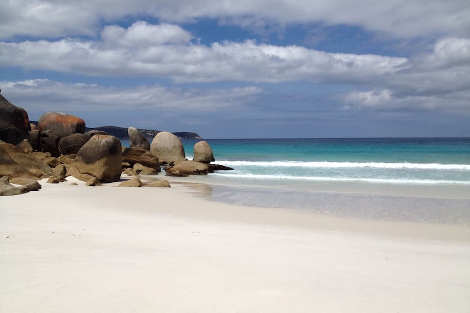 Uma praia com pedras grandes e águas turquesa calmas.