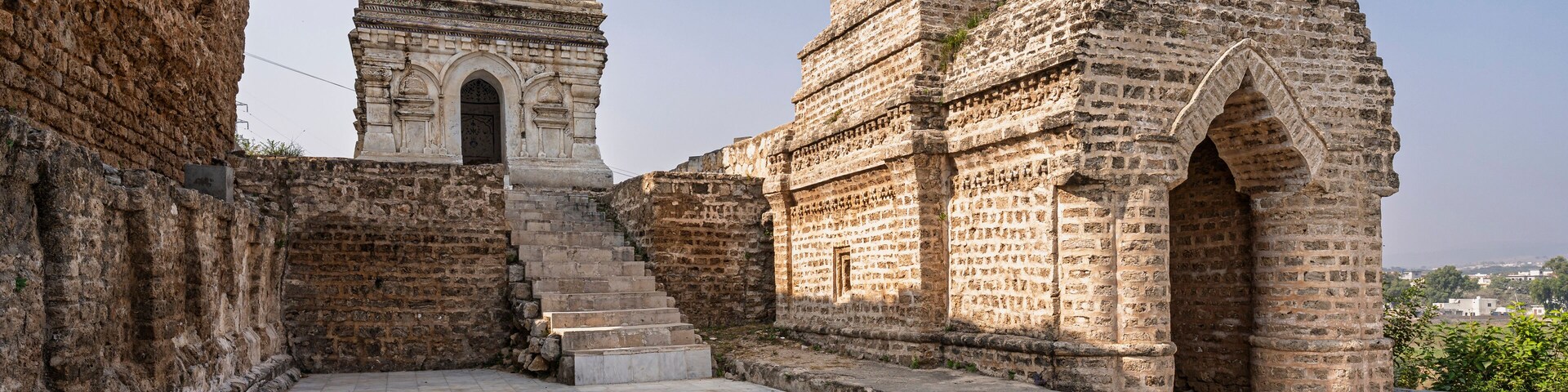 Uma estrutura de pedra antiga com uma torre de sino e uma grande porta em arco.