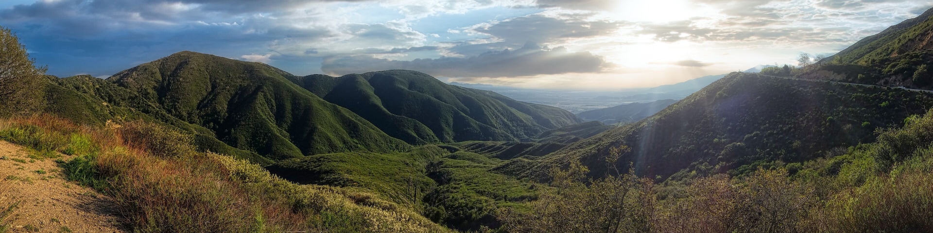 Paisagem montanhosa com vegetação exuberante e um caminho sinuoso.