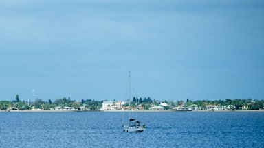 Um veleiro em um mar calmo, com uma vila costeira ao fundo.