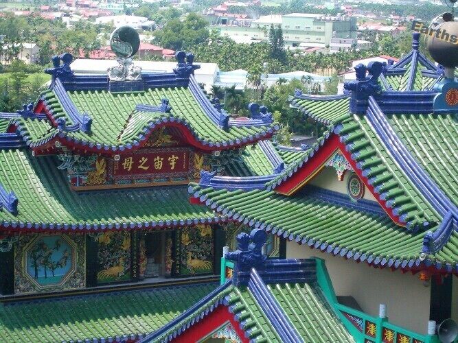 Telhados chineses tradicionais com detalhes ornamentais e um objeto esférico grande no topo.