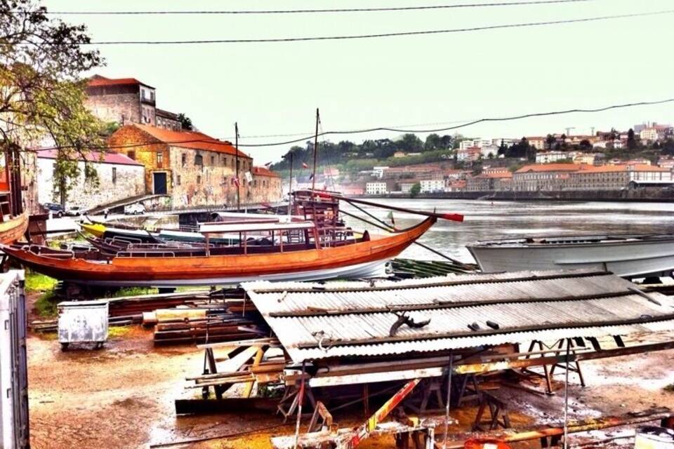 Um barco atracado em uma orla, com edifícios ao fundo.