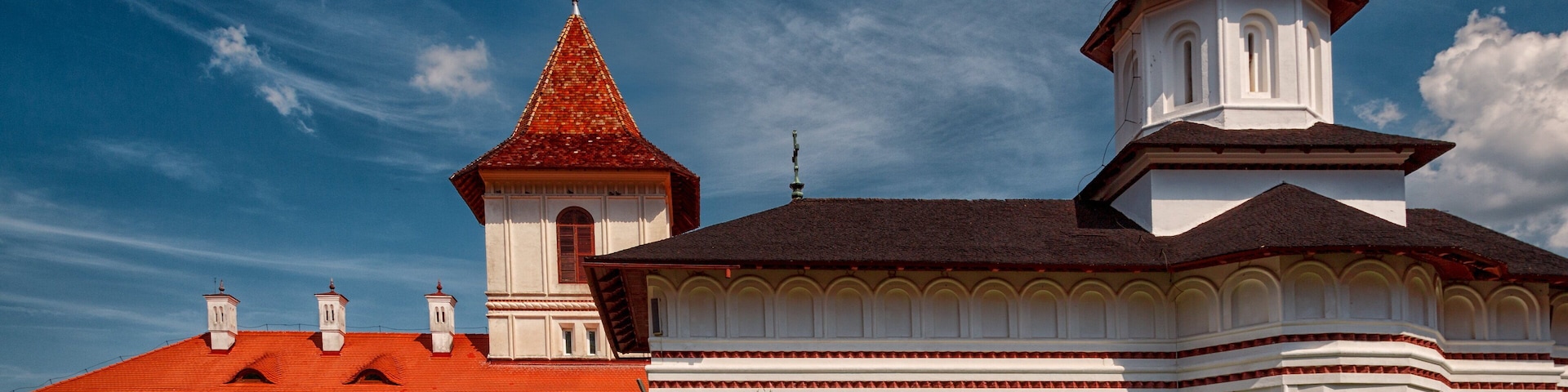 Uma igreja branca com telhado vermelho e uma torre alta.