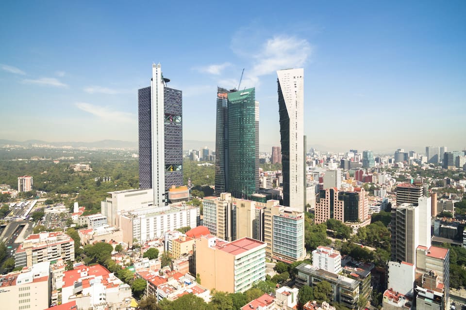 Paisagem urbana com arranha-céus modernos, edifícios urbanos densos e céu azul límpido.