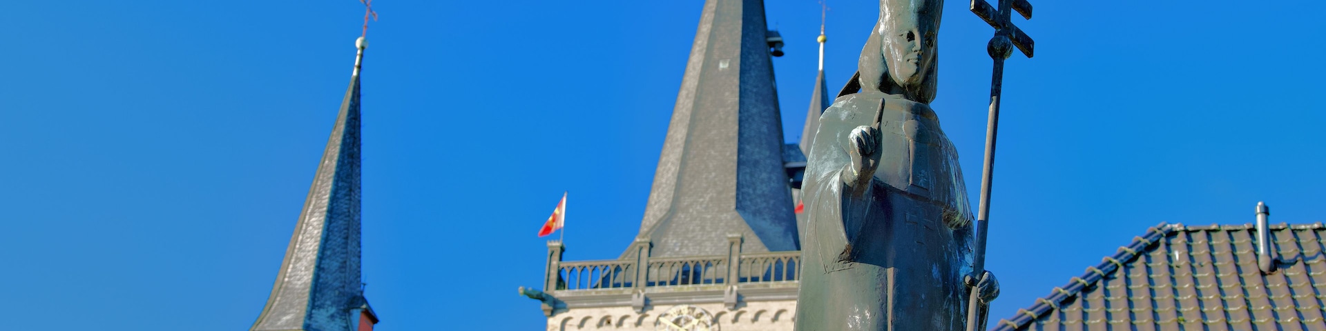 Uma igreja com duas torres, uma estátua e um relógio.