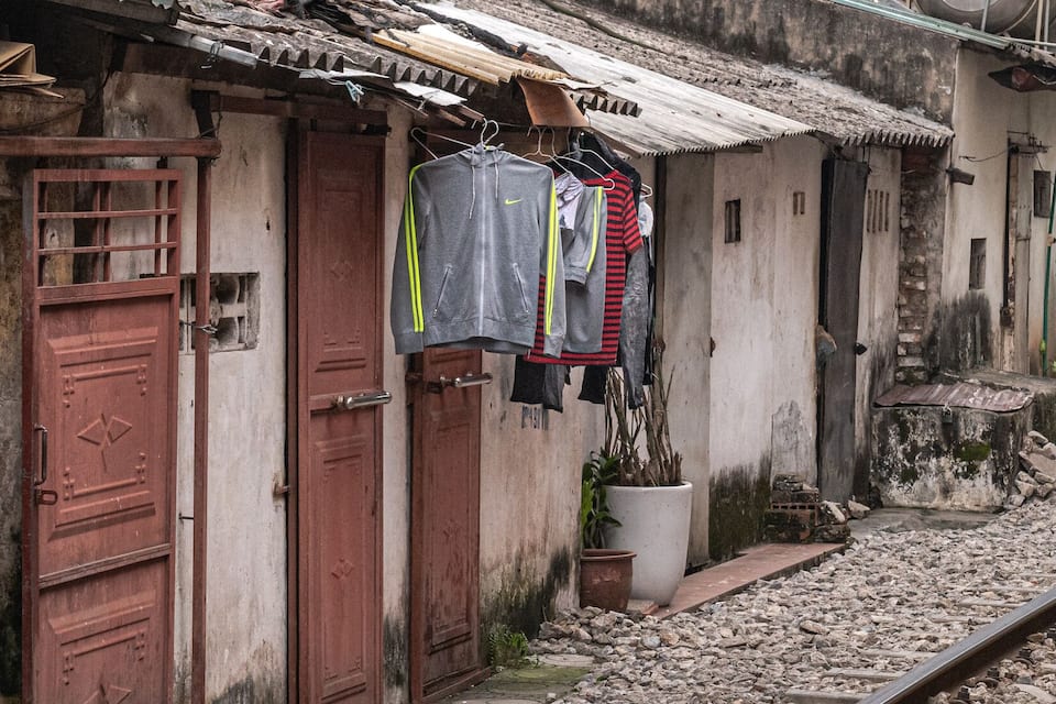Uma rua estreita com edifícios antigos, roupas penduradas em um varal e um trilho de trem.