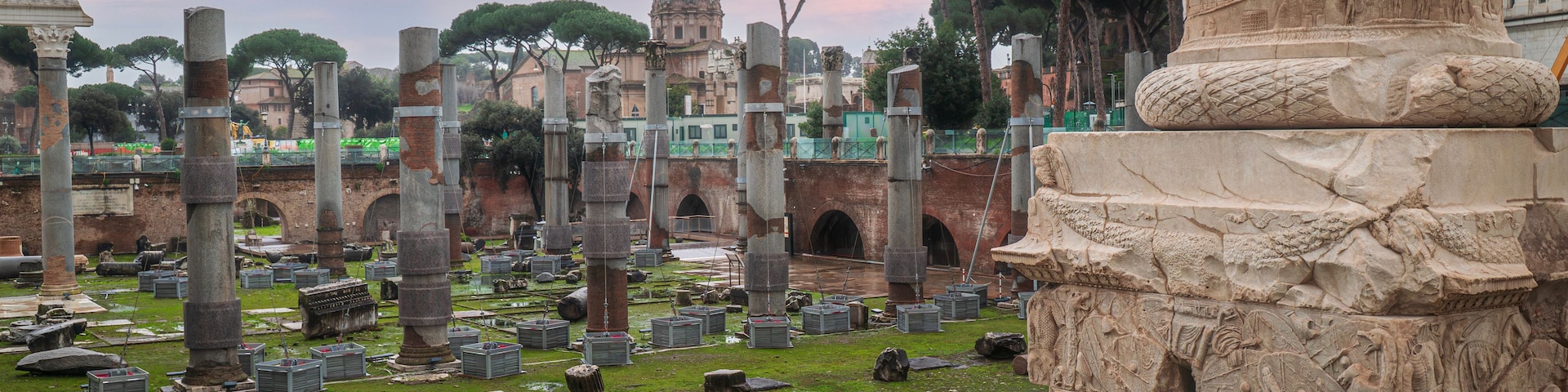 Ruínas antigas com colunas e um edifício abobadado ao fundo.