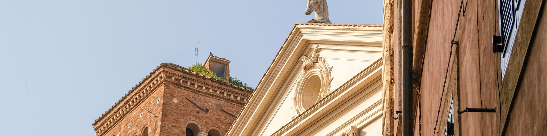 Uma igreja com cruz no topo, uma torre de tijolos e fachada branca.