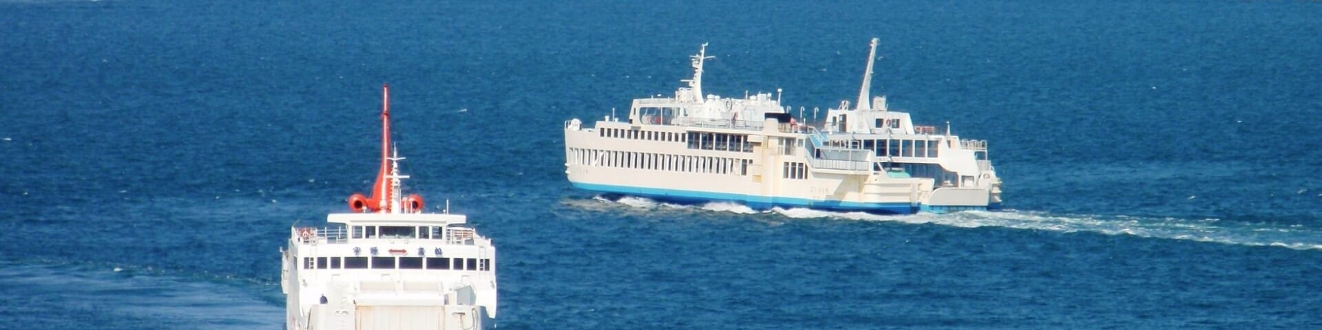 香川県高松市と岡山県玉野市を結ぶ宇高航路を航行するフェリー。左が四国フェリー(第八十七玉高丸)で右が宇高国道フェリー(こくどう丸)。高松港沖にて。