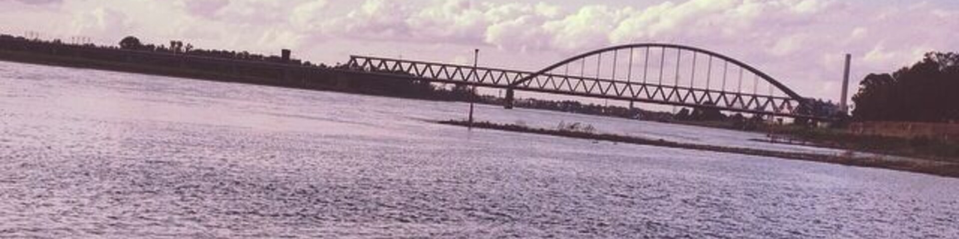 Uma ponte sobre um rio com margens rochosas em primeiro plano.