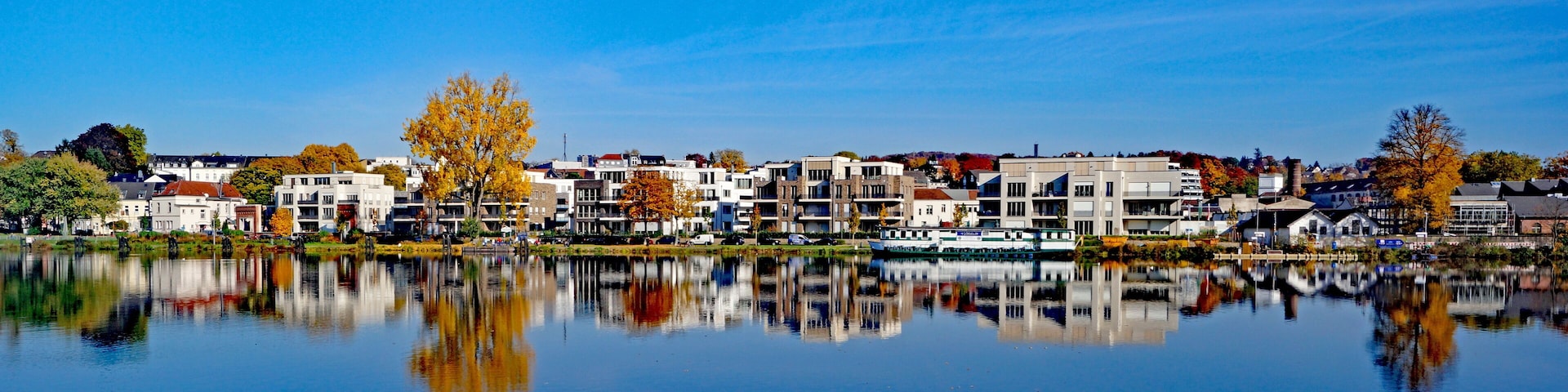 Um lago tranquilo refletindo edifícios e árvores.
