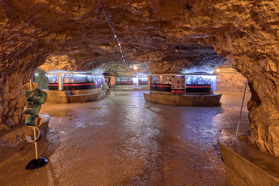 Caverna com exposições iluminadas e uma escadaria em espiral.
