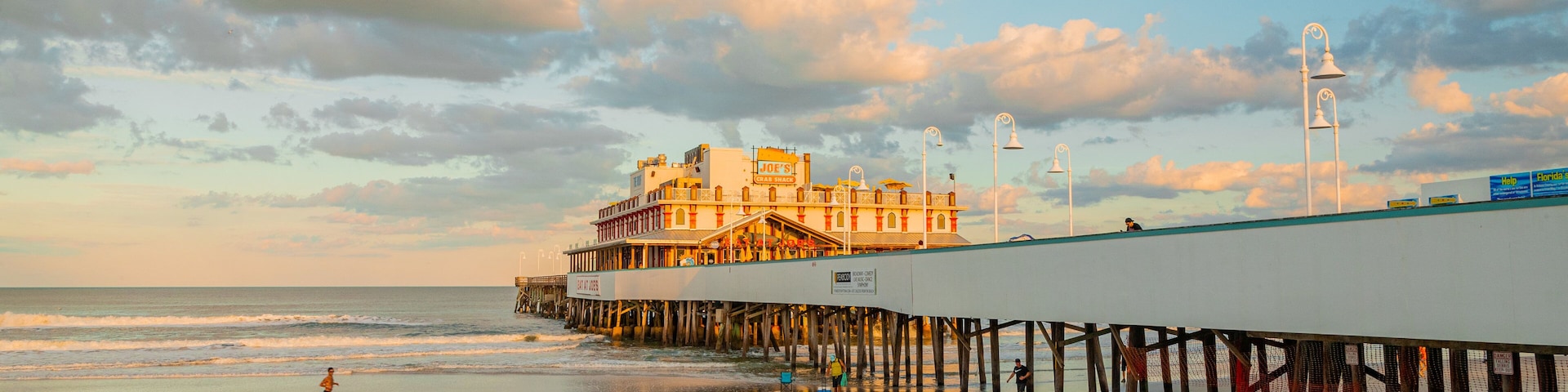 Uma praia com um cais e um edifício chamado "Joe's Crab Shack".