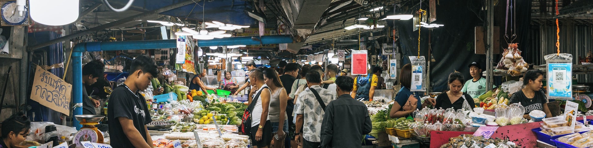 Um mercado interno movimentado, com diversos boxes oferecendo frutos do mar e vegetais.