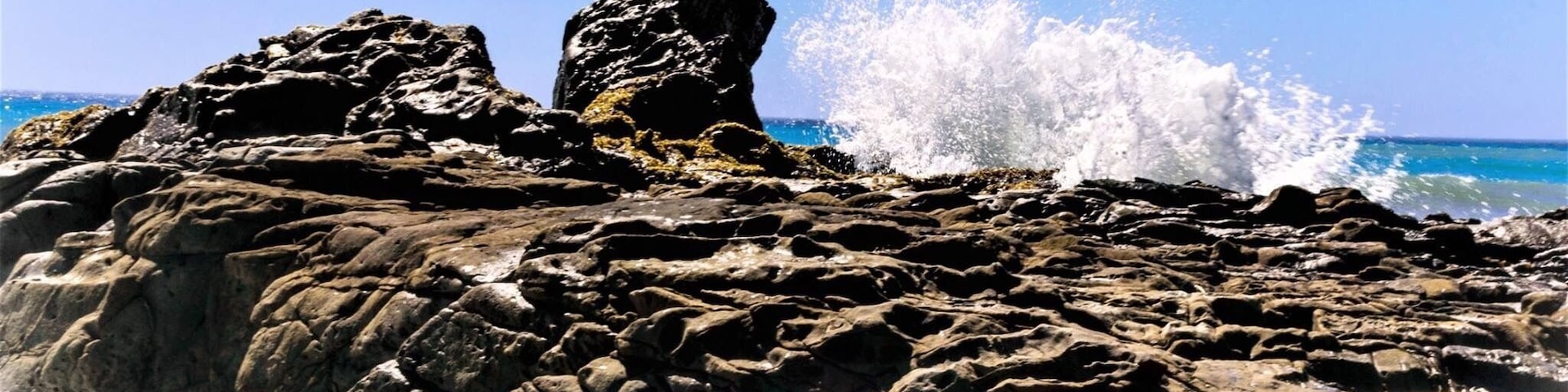 Uma costa rochosa com ondas quebrando nas pedras.