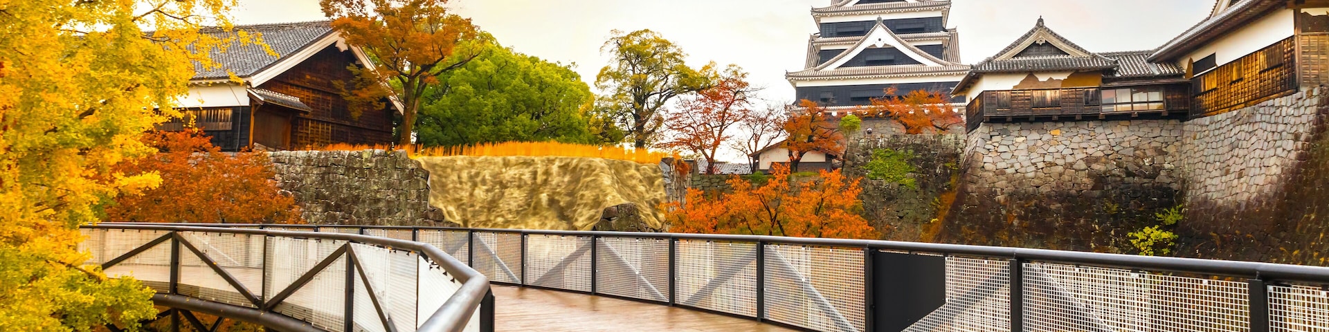 Uma ponte de madeira que leva a um castelo japonês tradicional, com folhagem de outono.
