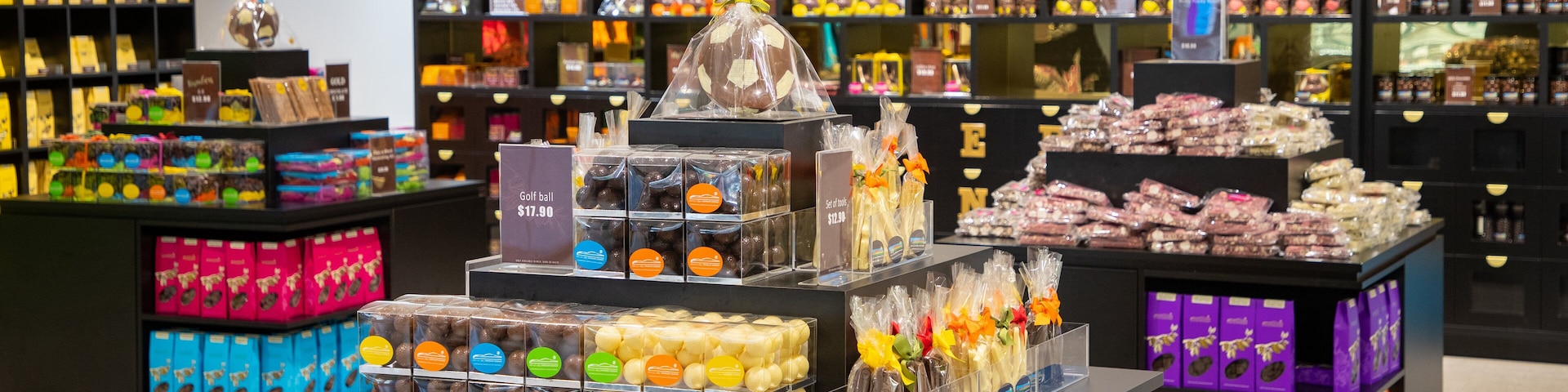 Uma loja de chocolates com diversos produtos em prateleiras e balcões.