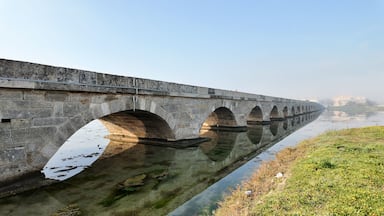 Uma ponte de pedra com várias abóbadas sobre um rio calmo.