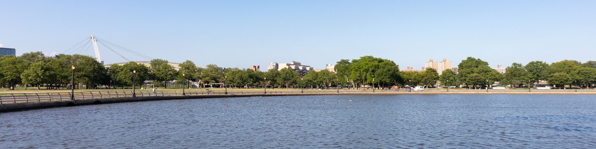 Um rio calmo com uma ponte ao fundo, rodeado por árvores e edifícios.