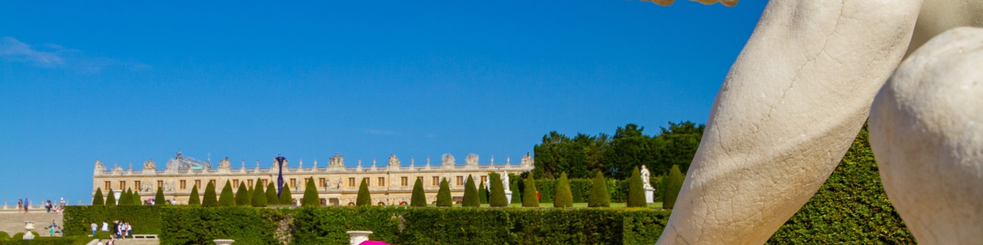 Versailles showing a garden and a statue or sculpture as well as a small group of people