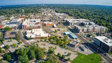 Vista aérea de uma cidade com edifícios comerciais, estacionamentos e áreas verdes.