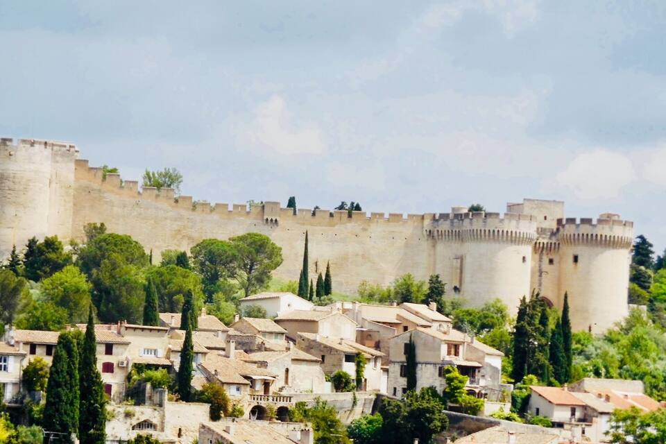 Um castelo medieval com muralhas fortificadas e uma cidade abaixo.