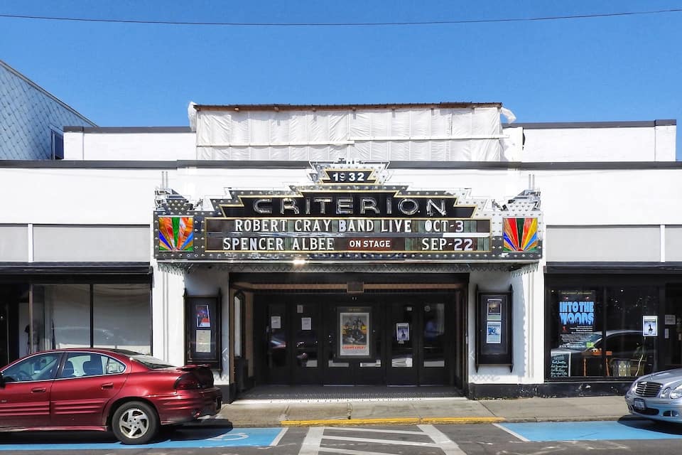 Uma marquise de teatro com o nome "Criterion" e programação de eventos para "Robert Cray Band ao Vivo" e "Spencer Albee no Palco".