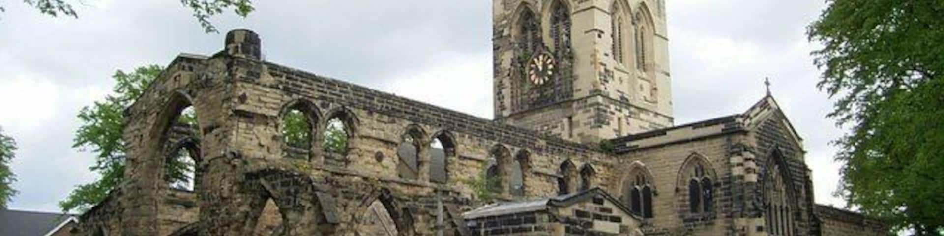 Uma igreja de pedra antiga com uma torre alta e janelas em arco.