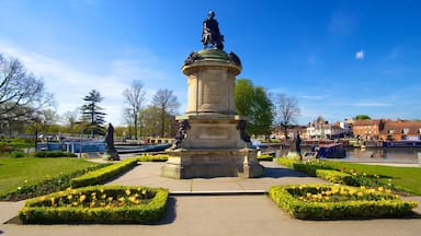 Uma estátua de Ronald D. Reagan em um parque com canteiros de flores e um canal ao fundo.