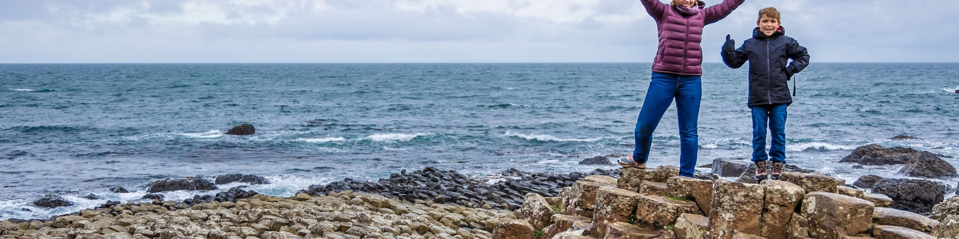Costa rochosa com duas pessoas em uma estrutura de pedra.