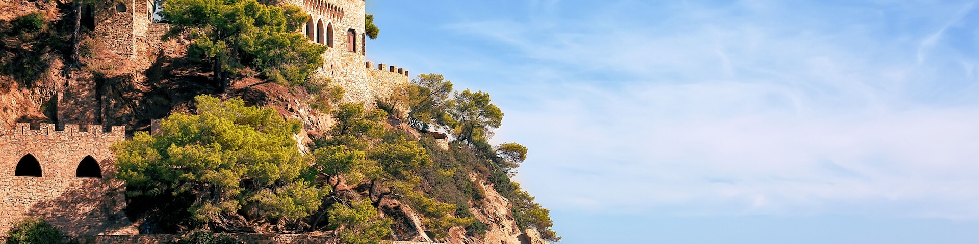 Um castelo à beira-mar erguido sobre um penhasco rochoso, com vista para o mar.