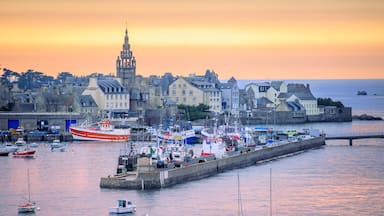 Um porto com barcos, um cais e edifícios históricos ao pôr do sol.