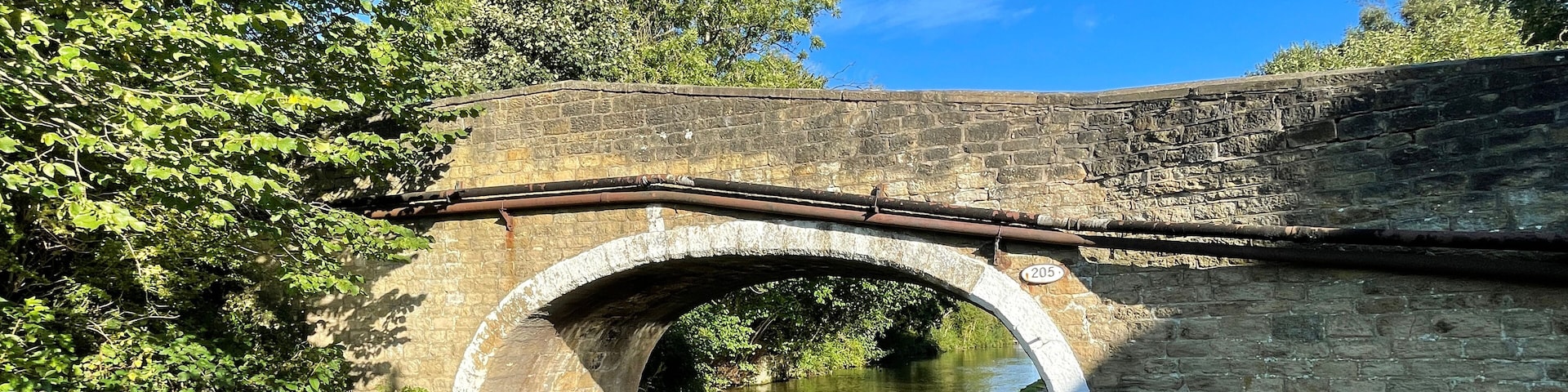 Uma ponte de pedra sobre um canal, com vegetação de ambos os lados.