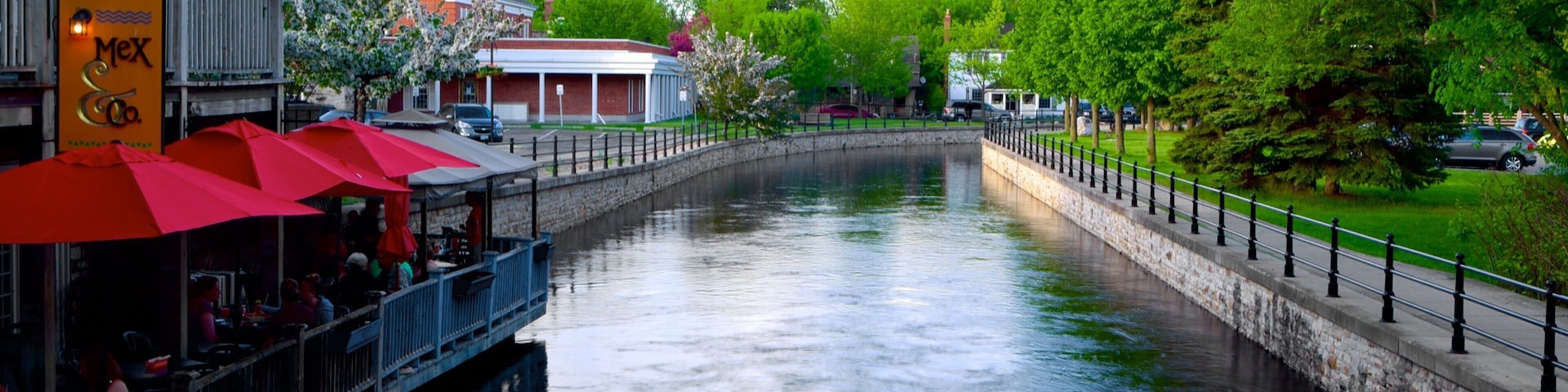 Um canal com um restaurante à esquerda e uma ponte ao fundo.