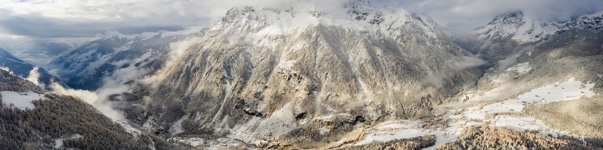 Cordilheira nevada com um vale e edifícios dispersos.