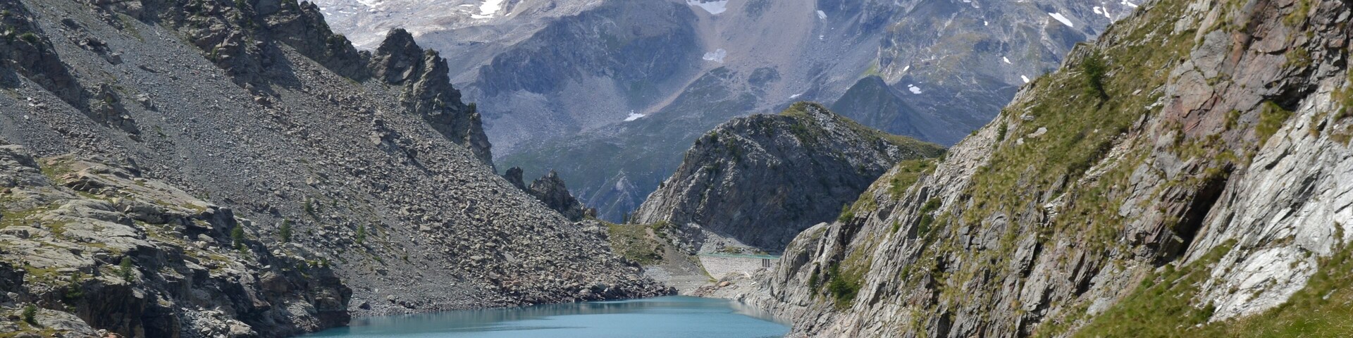 Um lago montanhoso rodeado por picos acidentados e montanhas nevadas.