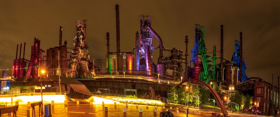 Um complexo industrial noturno com estruturas iluminadas e um grande edifício central.