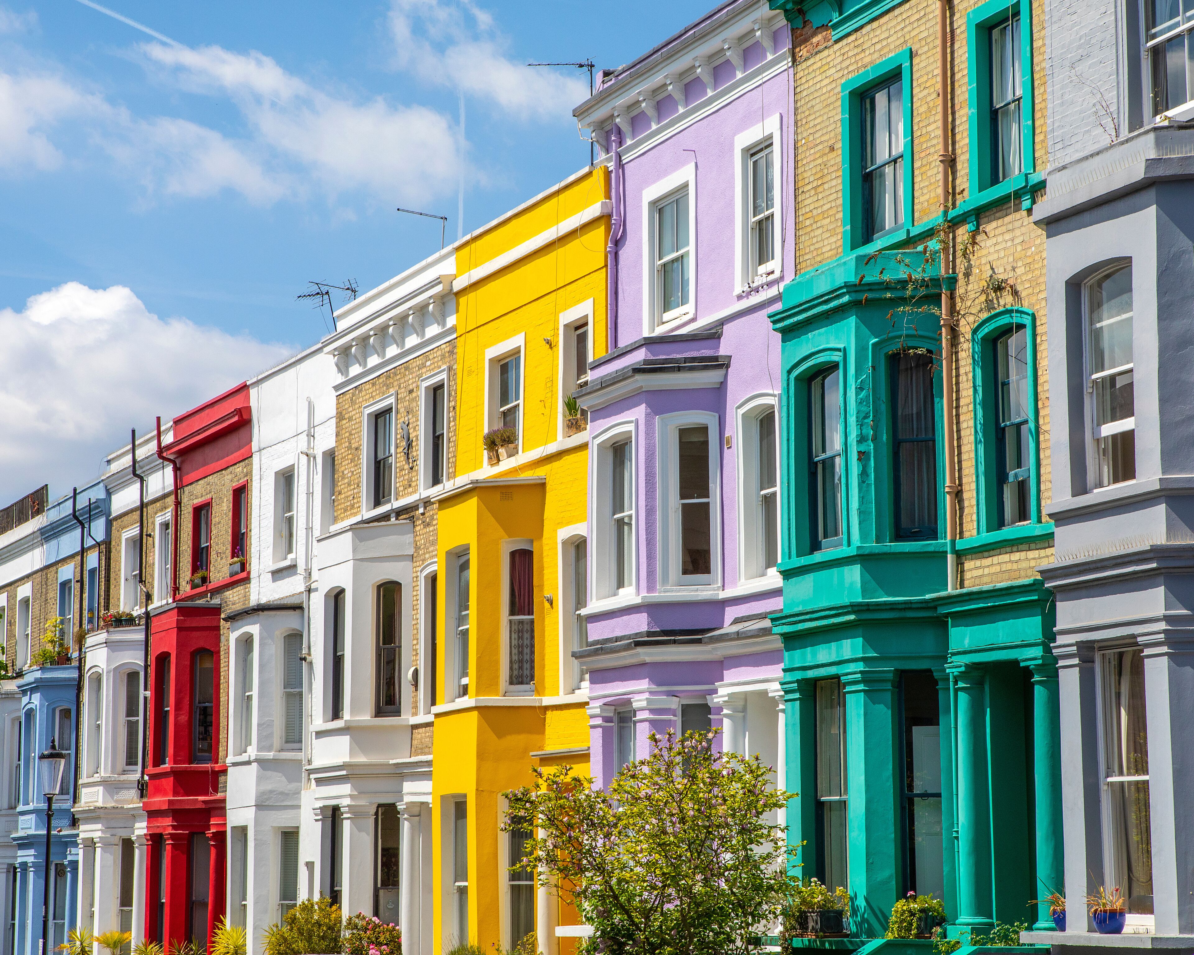 Uma fileira de casas geminadas em estilo vitoriano, com cores pastel vibrantes e detalhes arquitetônicos clássicos.
