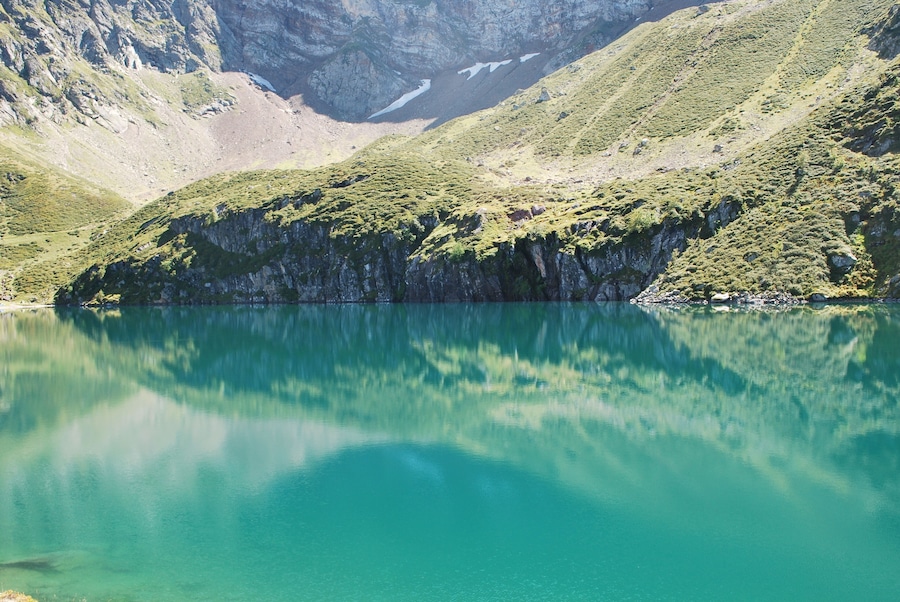 Um lago montanhoso rodeado por terreno acidentado e vegetação escassa.
