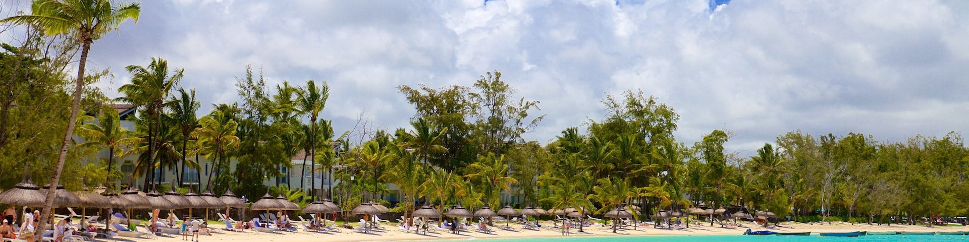 Uma praia tropical com águas turquesa cristalinas, palmeiras e guarda-sóis de praia.