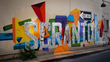 Um mural colorido com formas geométricas e a palavra 'SECRETION' numa parede de tijolos.