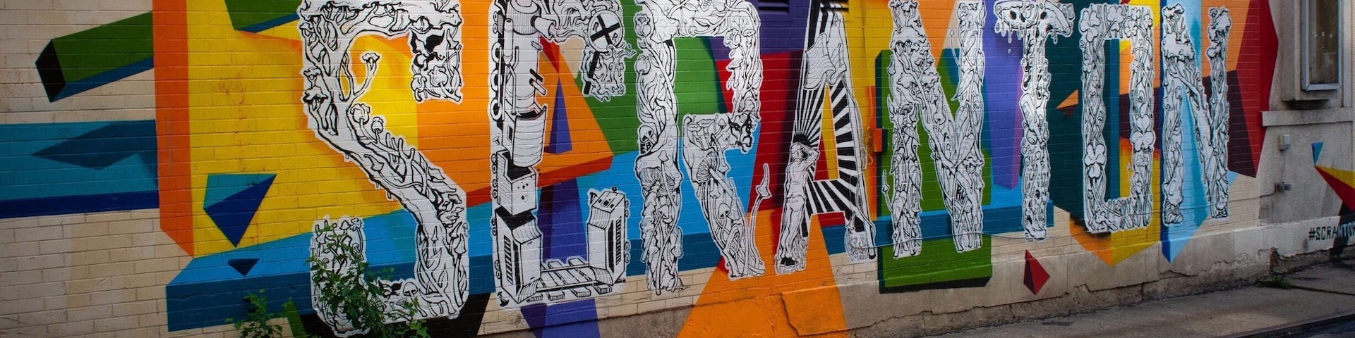 Um mural colorido com formas geométricas e a palavra 'SECRETION' numa parede de tijolos.